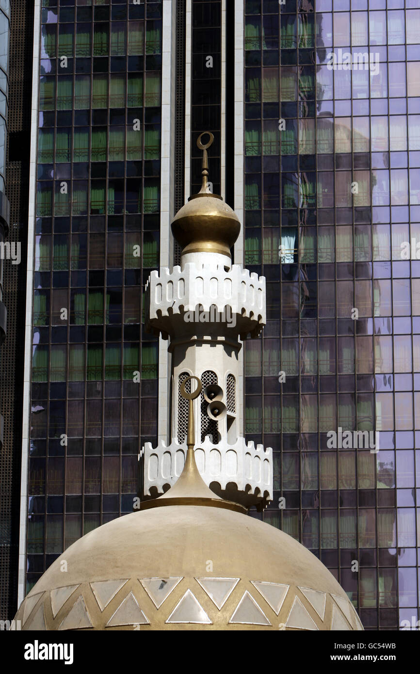 The minaret of a Mosque sits infront of an office block in downtown Abu ...