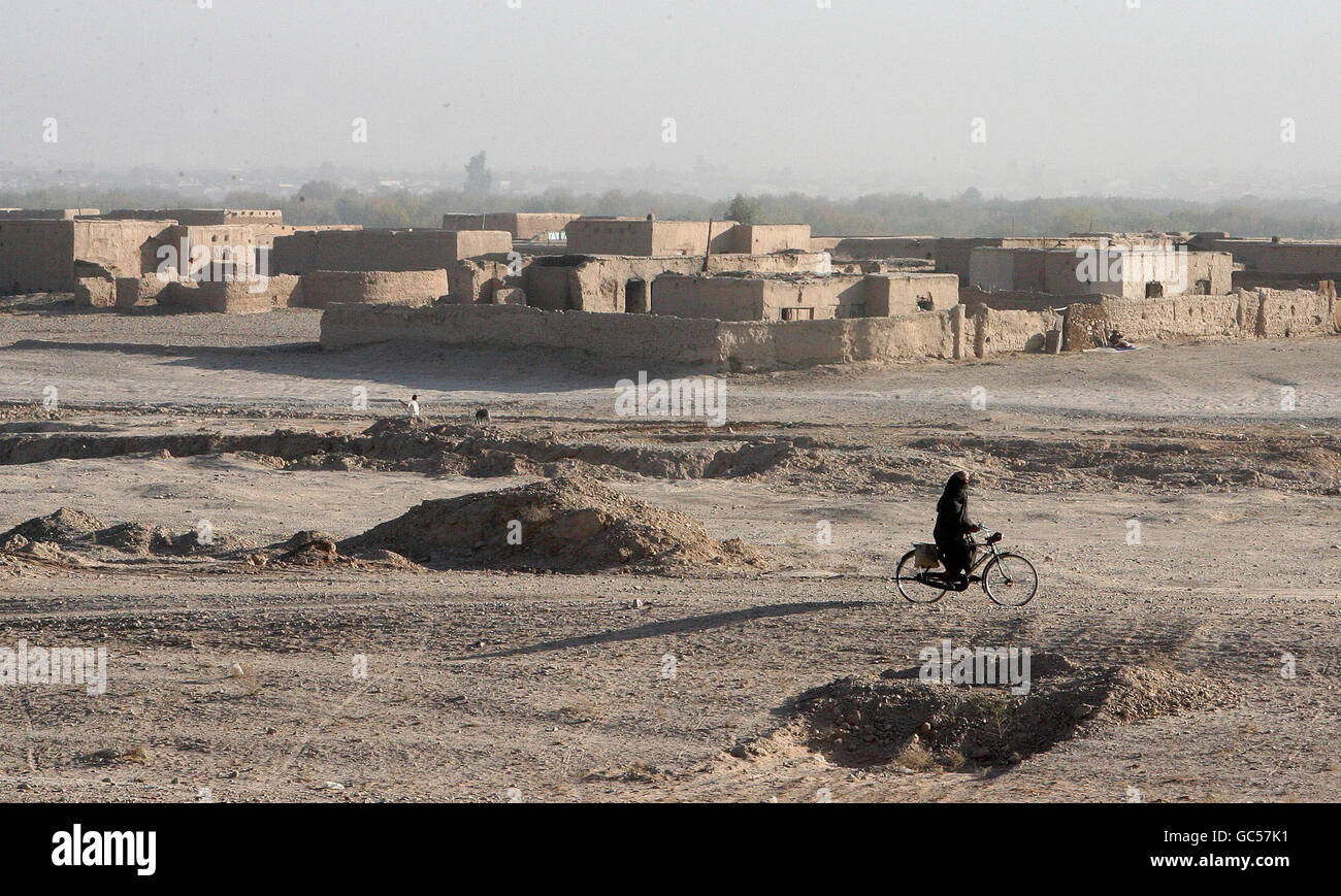 An Afghan rides a bicycles past a village in an area west of Lashkar ...
