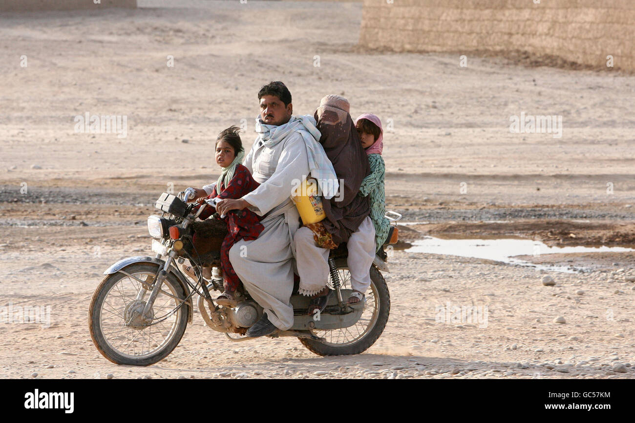 Afghan ride a motorbike past a village in an area west of Lashkar Gah ...