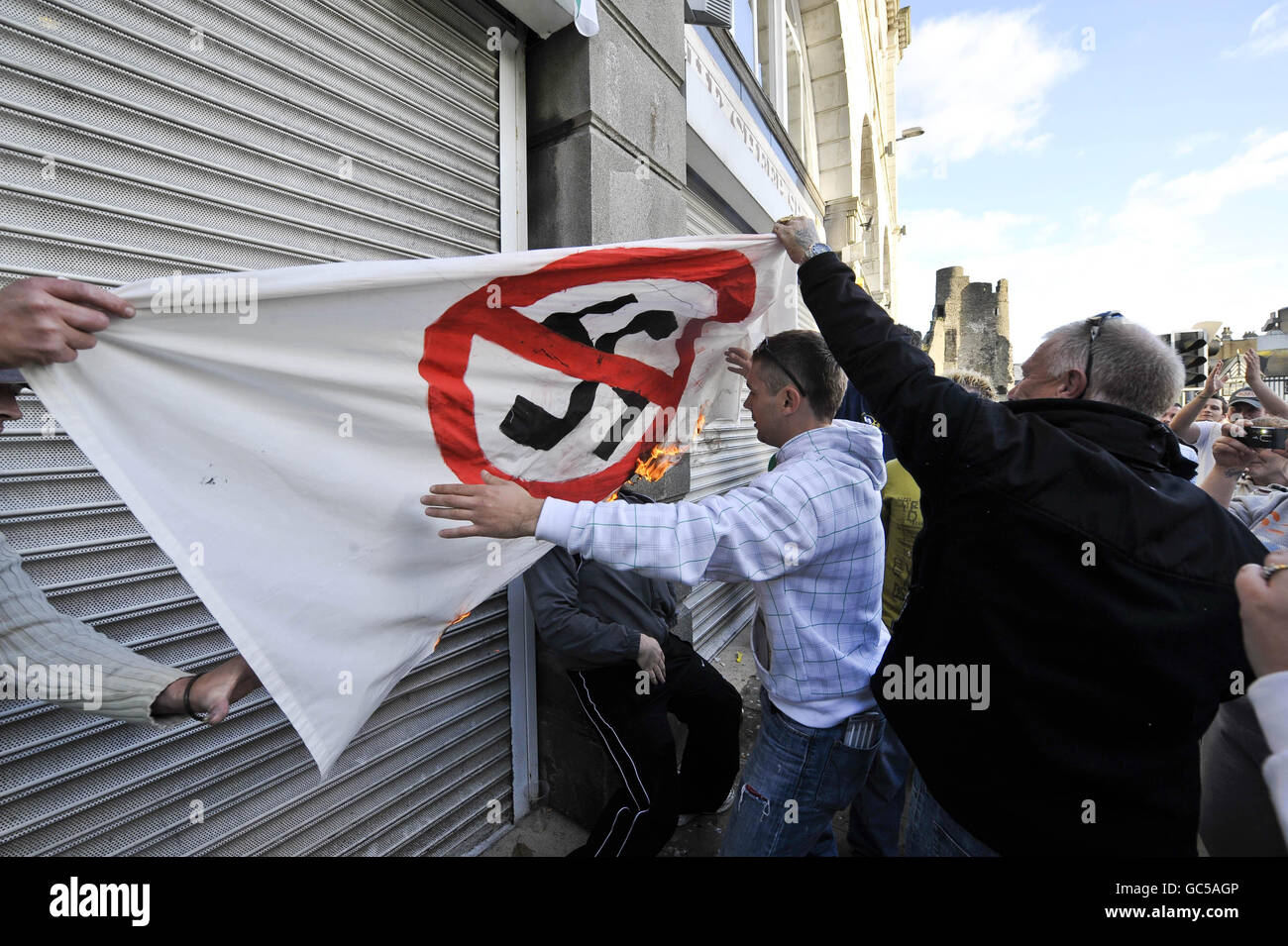 Welsh Defence League protesters burn an anti-Nazi flag during a protest ...