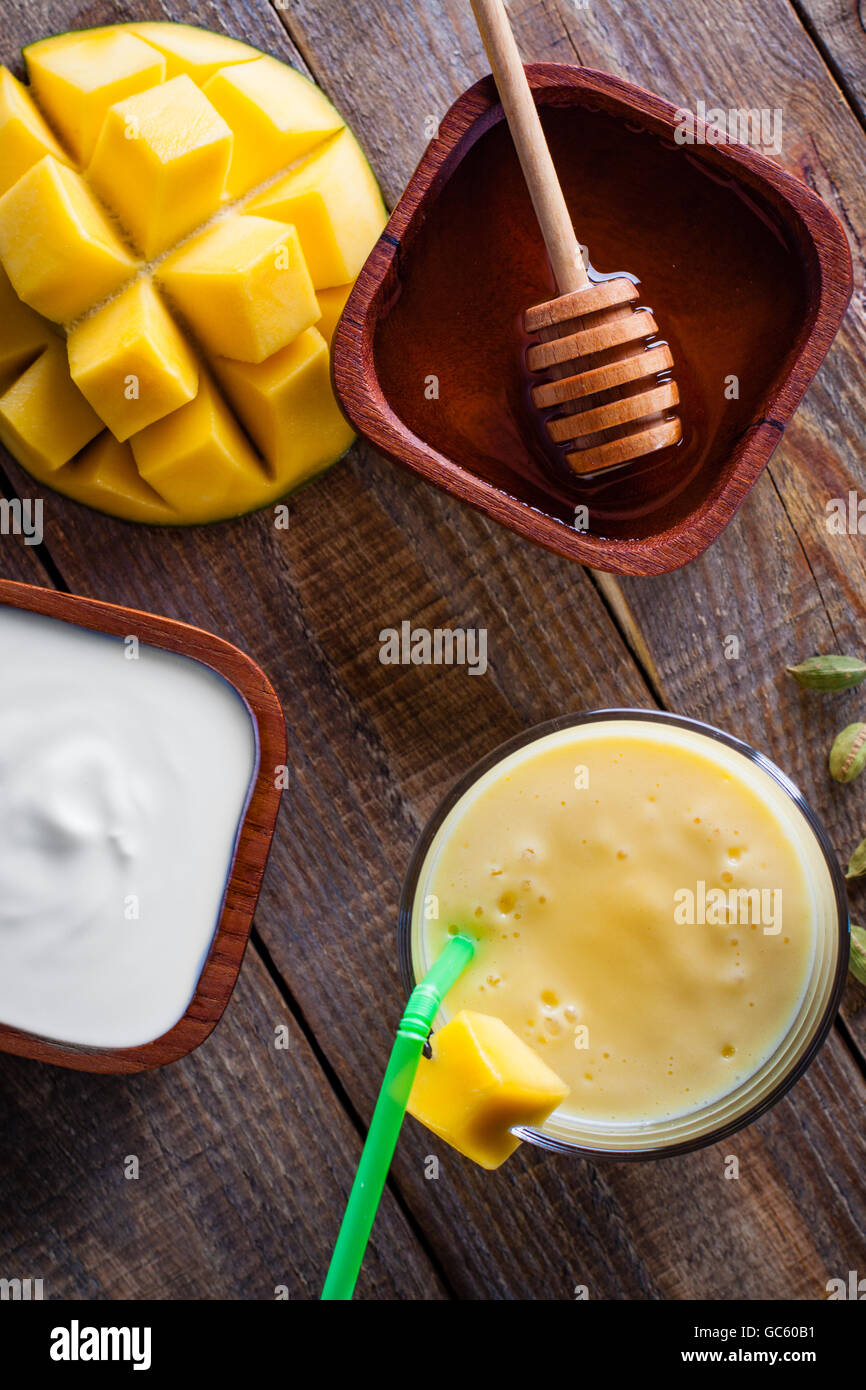 Overhead, glass of milkshake made of mango and yoghurt with sweet honey ...