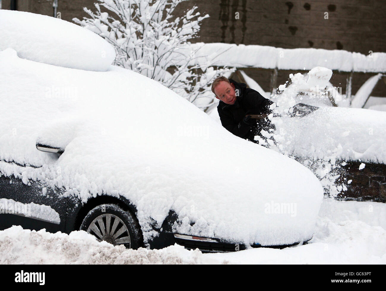 A man clears snow from his car in St Boswells in the Scottish Borders after a night of heavy ...