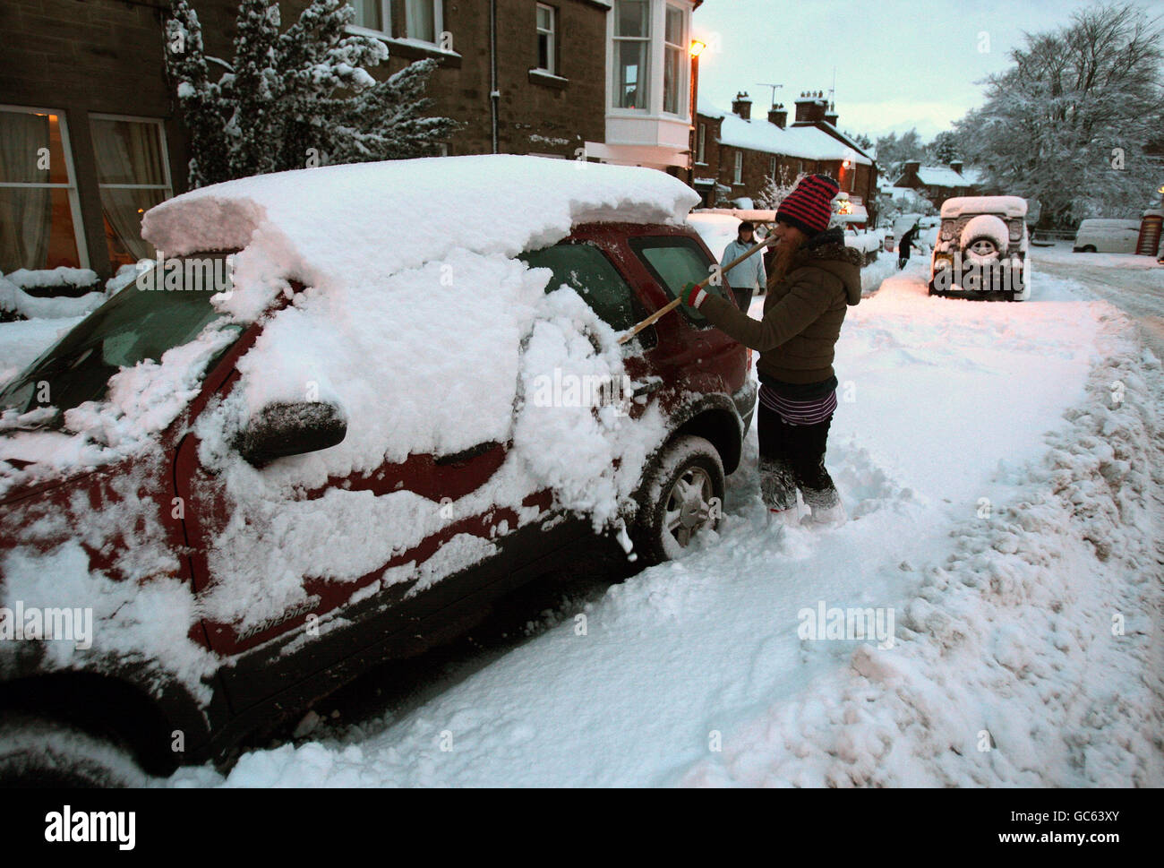 Winter weather. A woman clears snow from her car in St Boswells in the Scottish Borders, after a ...