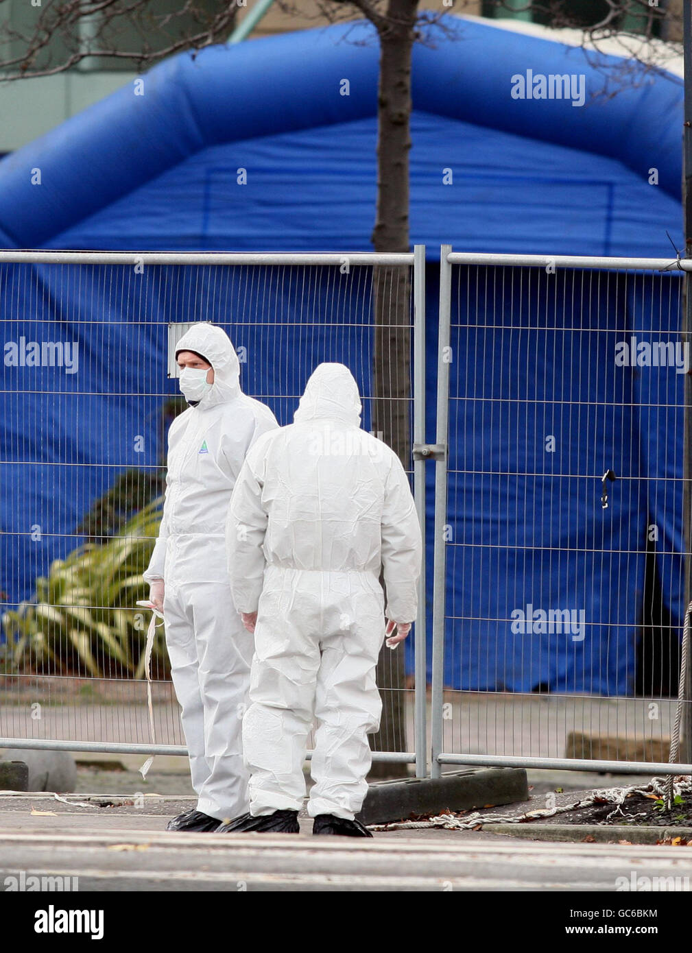 Police forensic officers examine the area around a car which partially ...