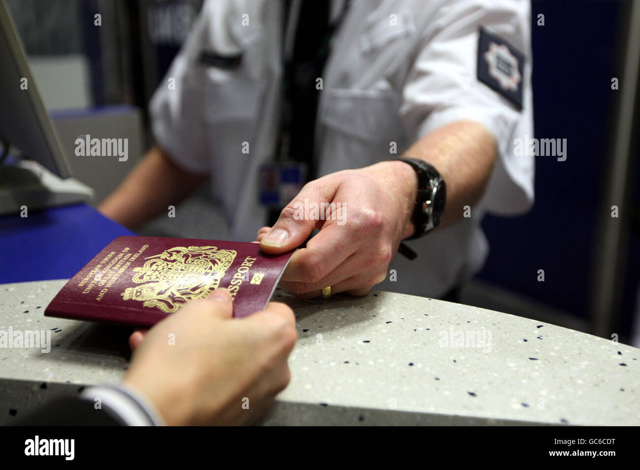 A UK Border Agency officer checks a passport in the North Terminal of ...