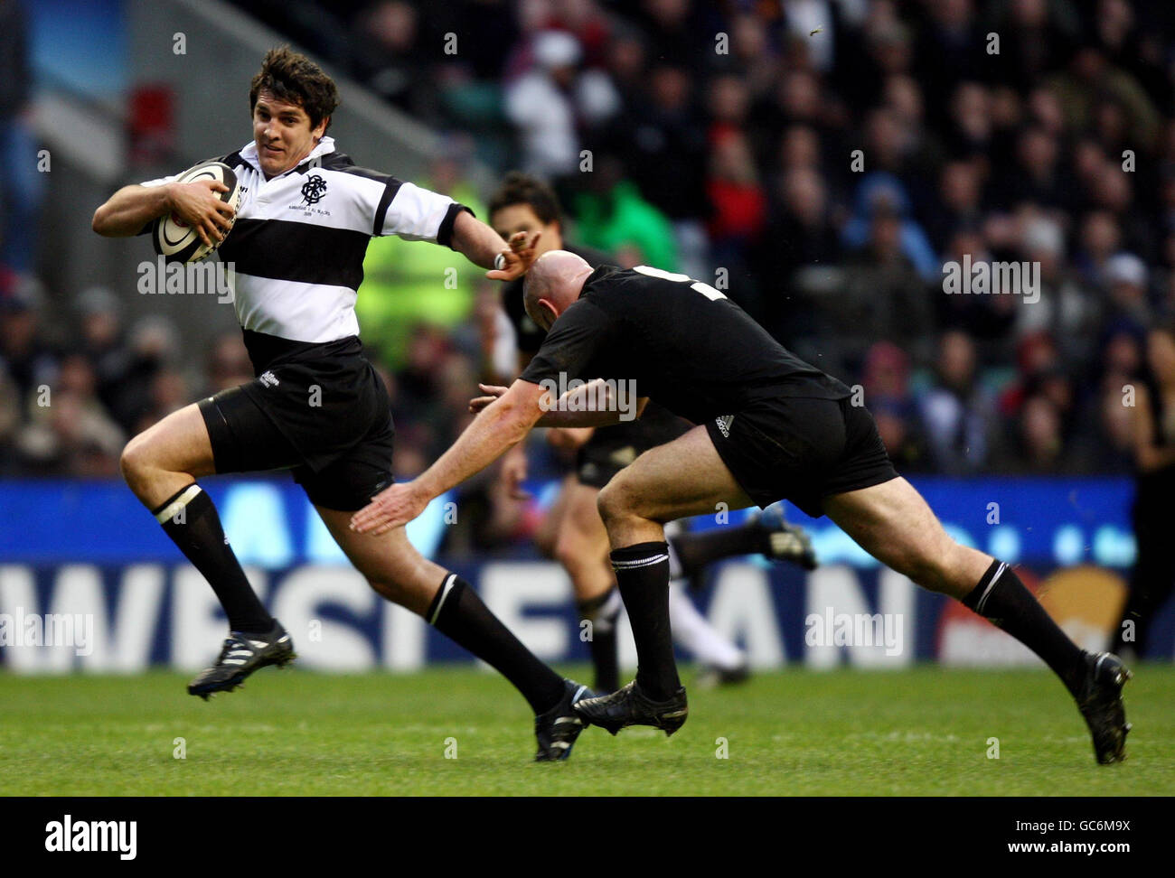 Barbarians' Jaque Fourie hands off the tackle of New Zealand's Brendon ...