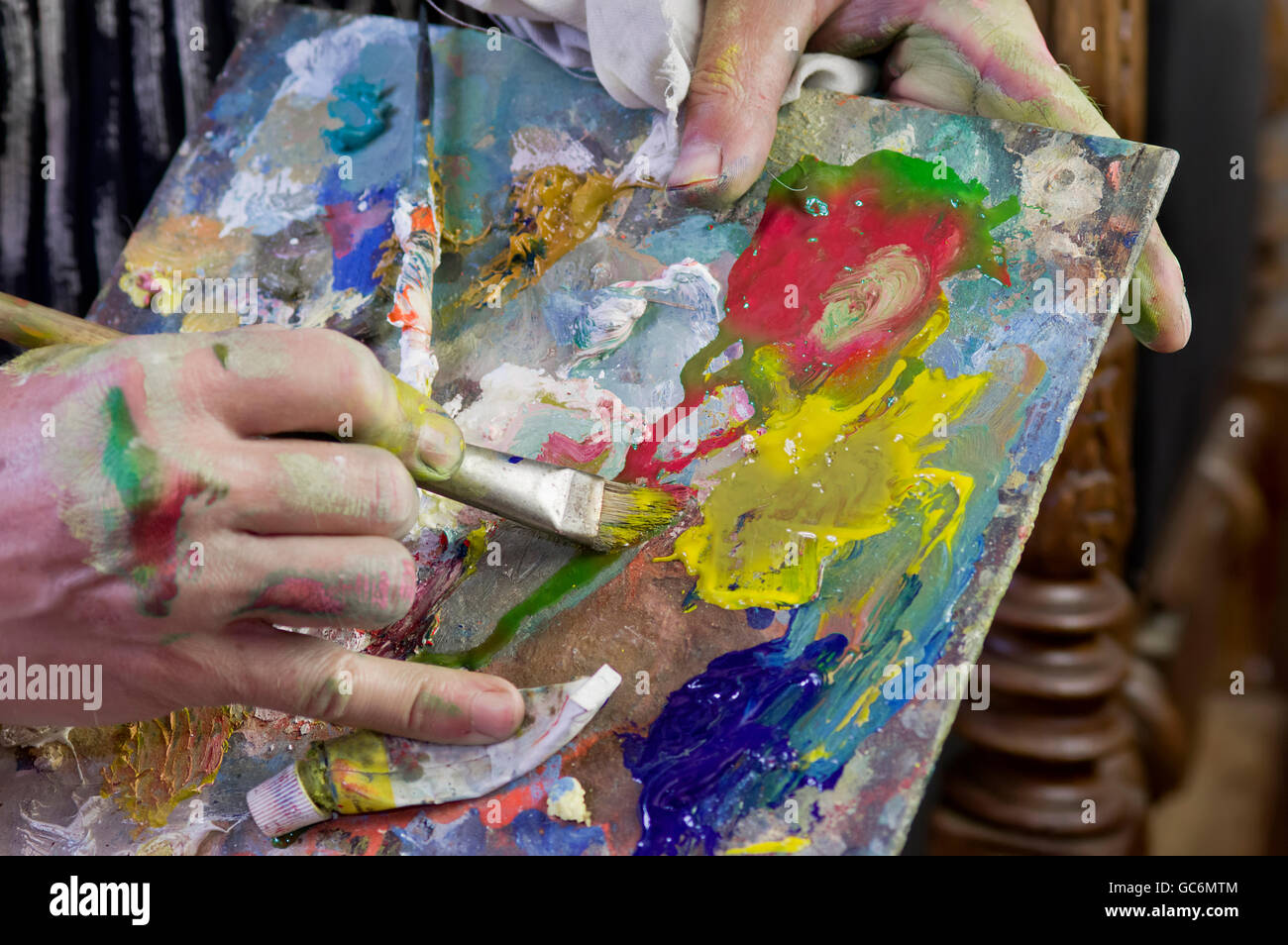 Artist hand with paint brush mixing colors on an artist palette ...