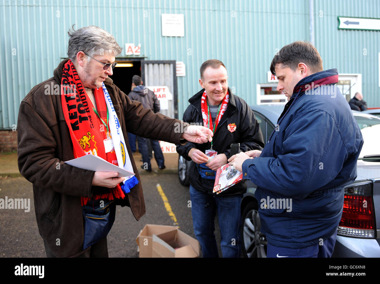 A fan buys a matchday programme from a seller outside of the ground ...