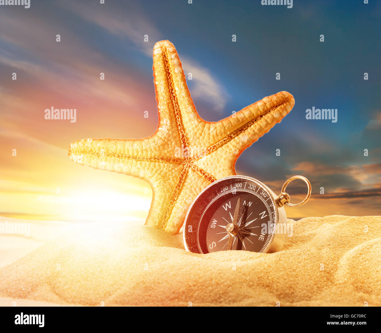Sea star and compass in sand on sunset background Stock Photo - Alamy