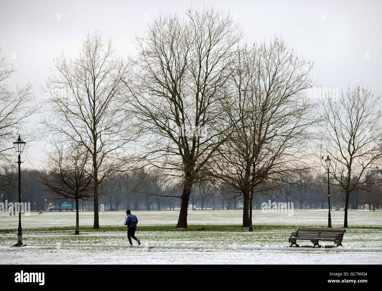 A man jogs as snow still covers the ground on Clapham Common, London ...
