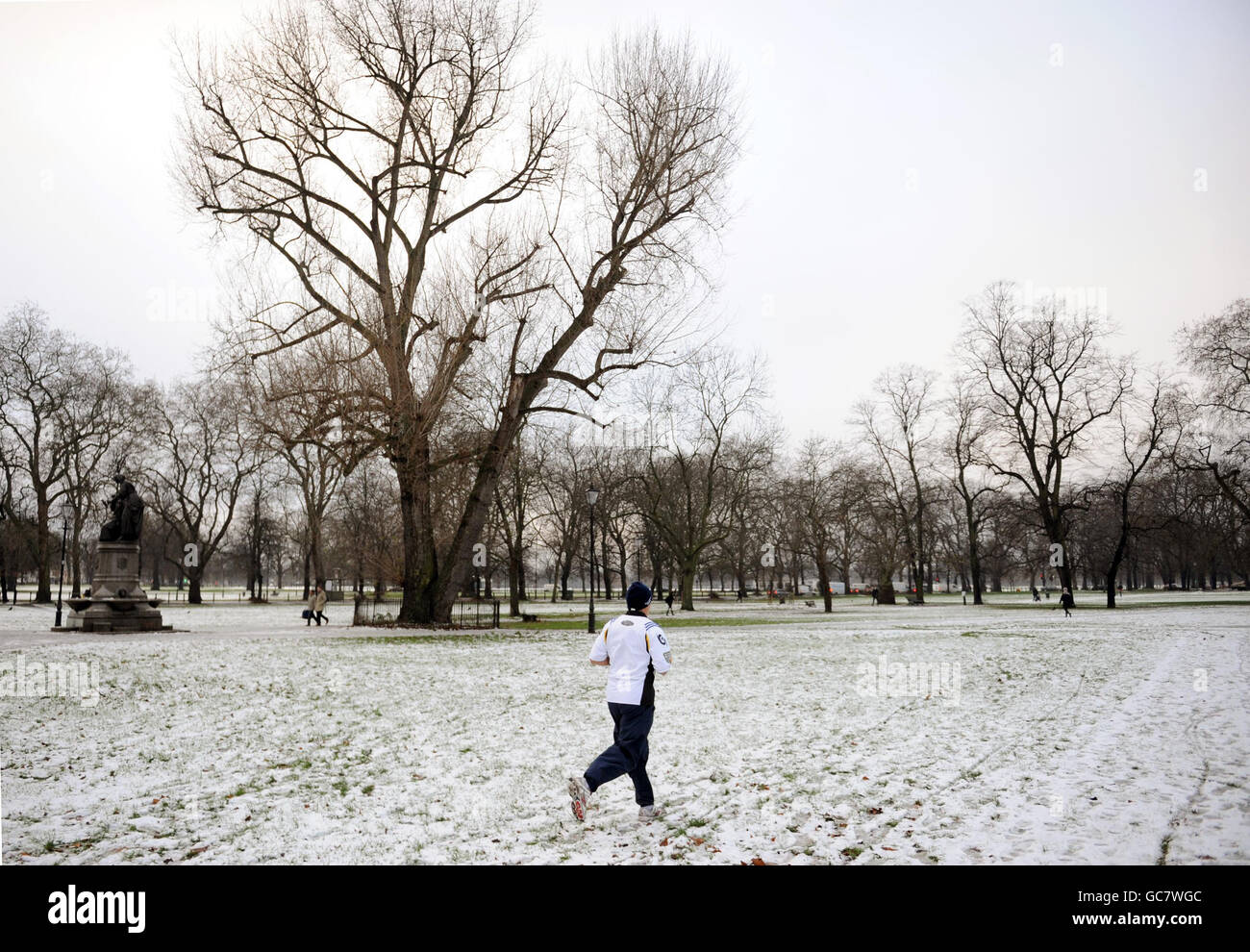 A man jogs as snow still covers the ground on Clapham Common, London ...