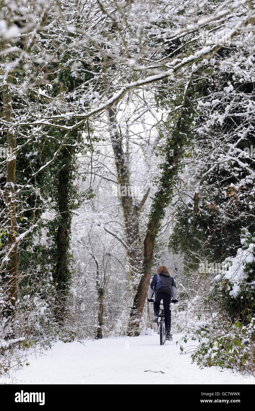 Winter weather. A man cycles along a snow covered path following ...
