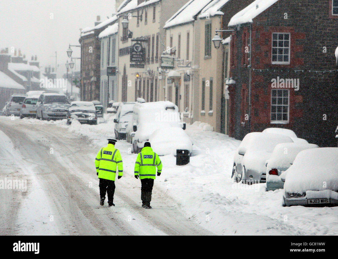Police walk through the snow in the town of Lauder after a night of ...
