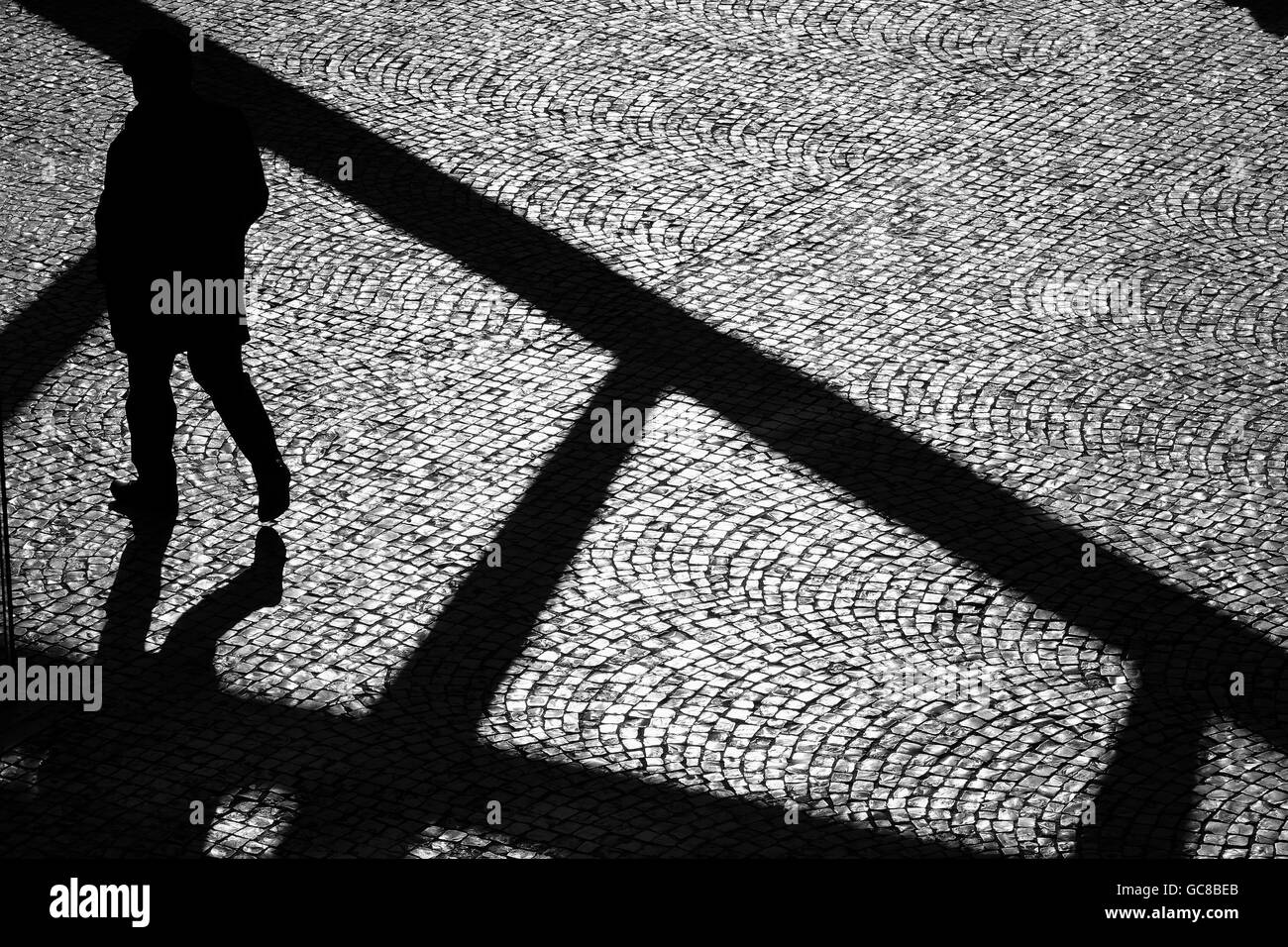 Shadows being cast strong sunlight and by people walking on cobbled ...