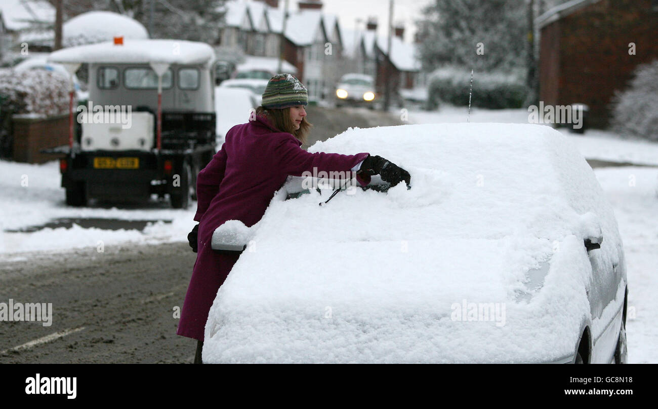 Krystyna Rudzki removes snow from her car before leaving for work as snow causes problems in ...
