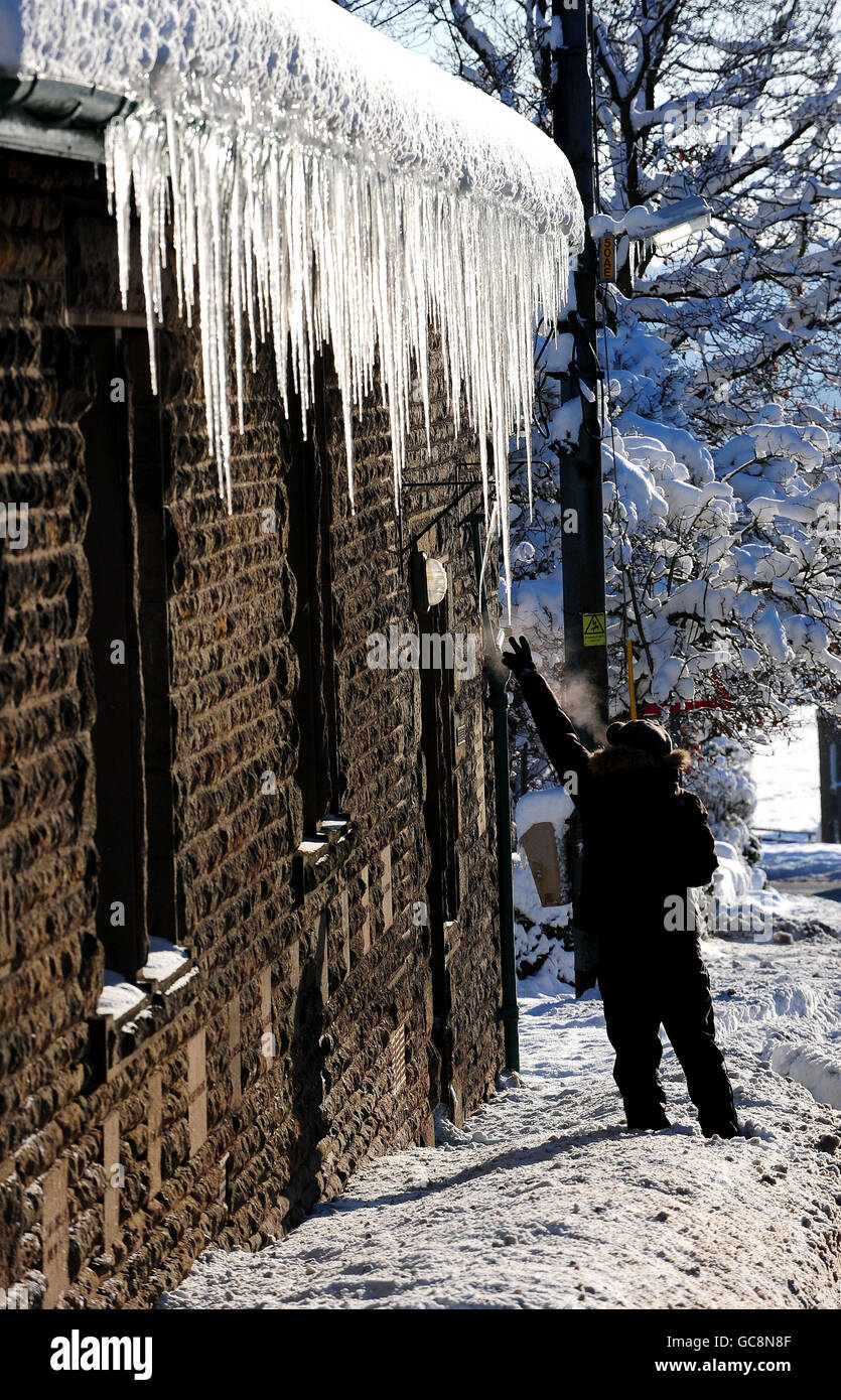 A passer by reaches up to giant icicles in Catton, Northumberland after ...