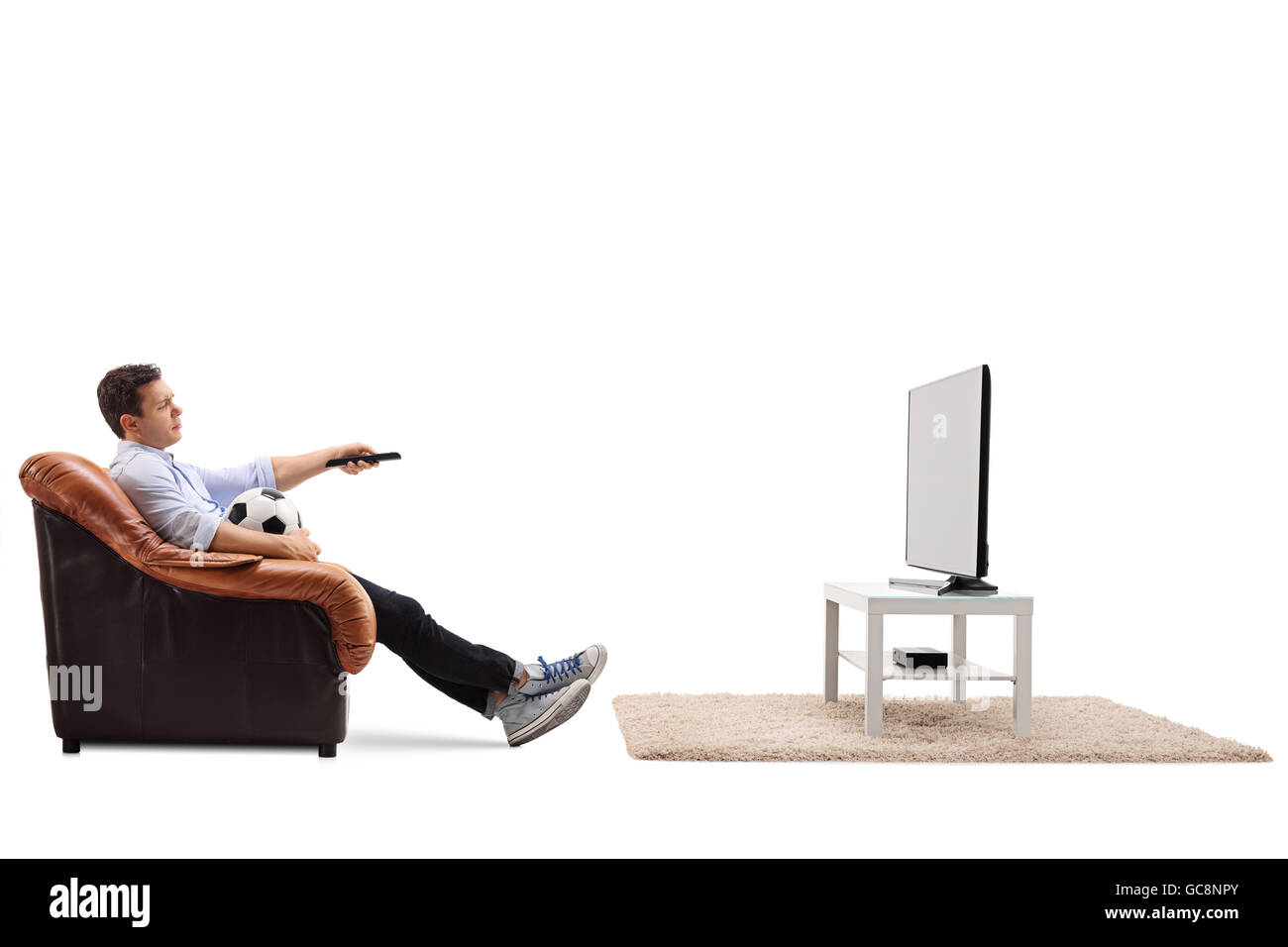 Bored young guy watching football on TV and changing the channel ...