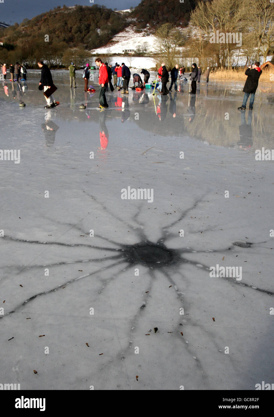 A crack in the ice near to where curlers play on the wet surface of the ...