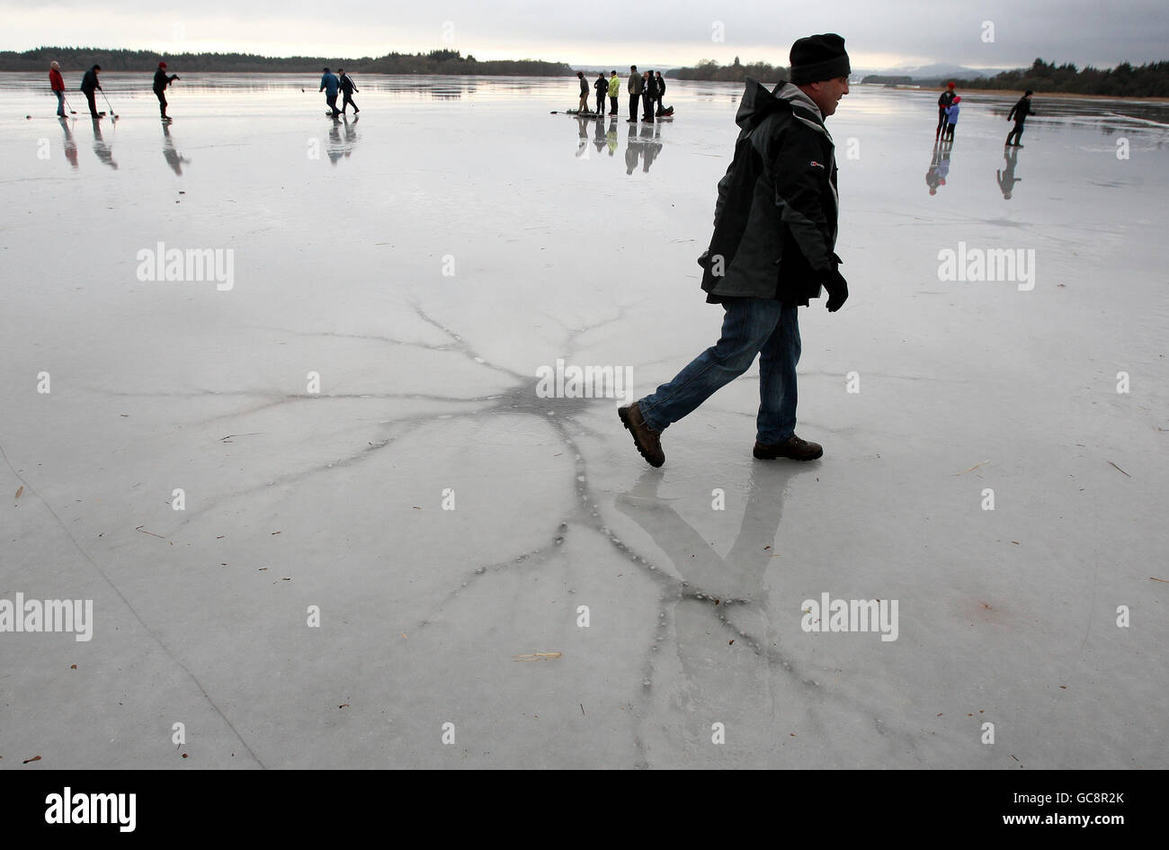 A curler plays a game near a crack in the ice on the wet surface of the ...