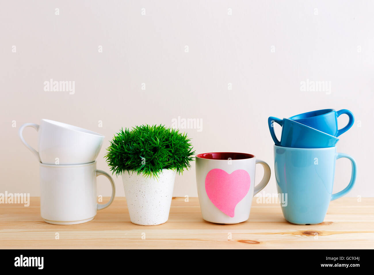 Mug and cup stack and white cups on wood kitchen table Stock Photo - Alamy