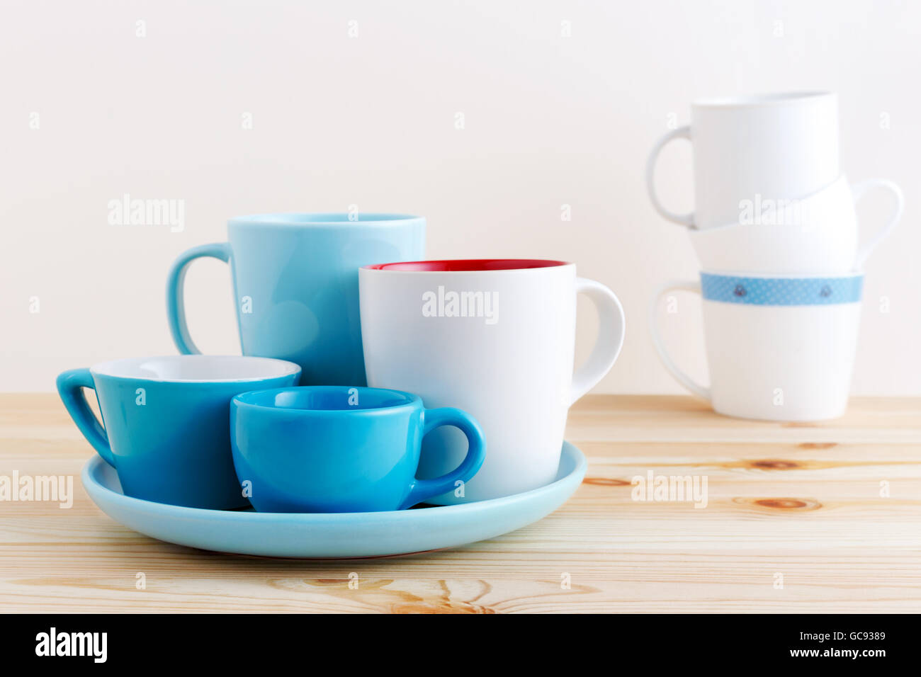 Blue cups and white mug on plate on wooden table Stock Photo - Alamy