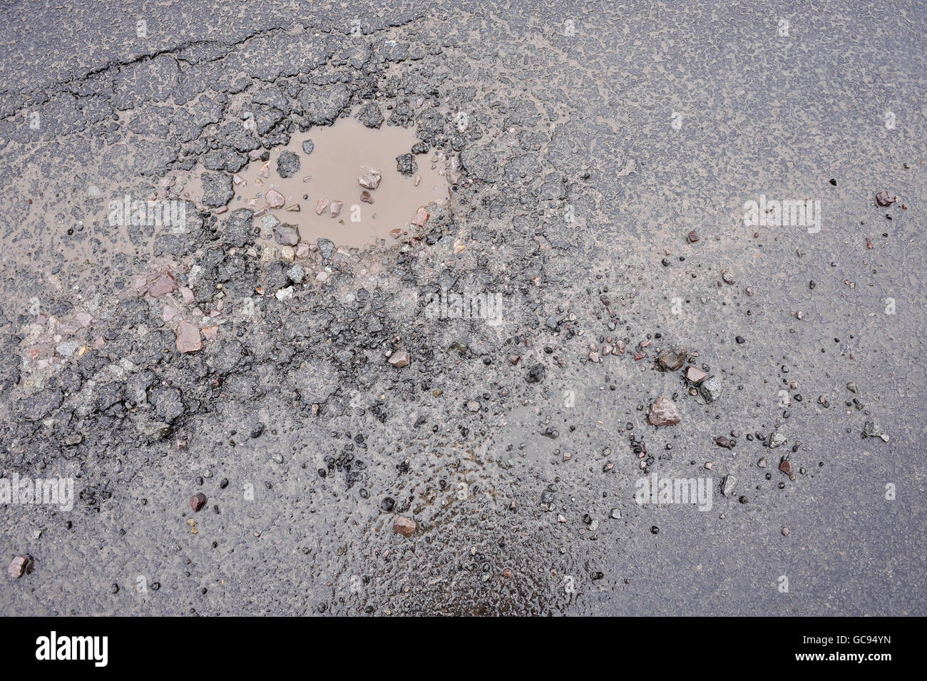 A pothole begins to form with a series of cracks and loose debris after ...