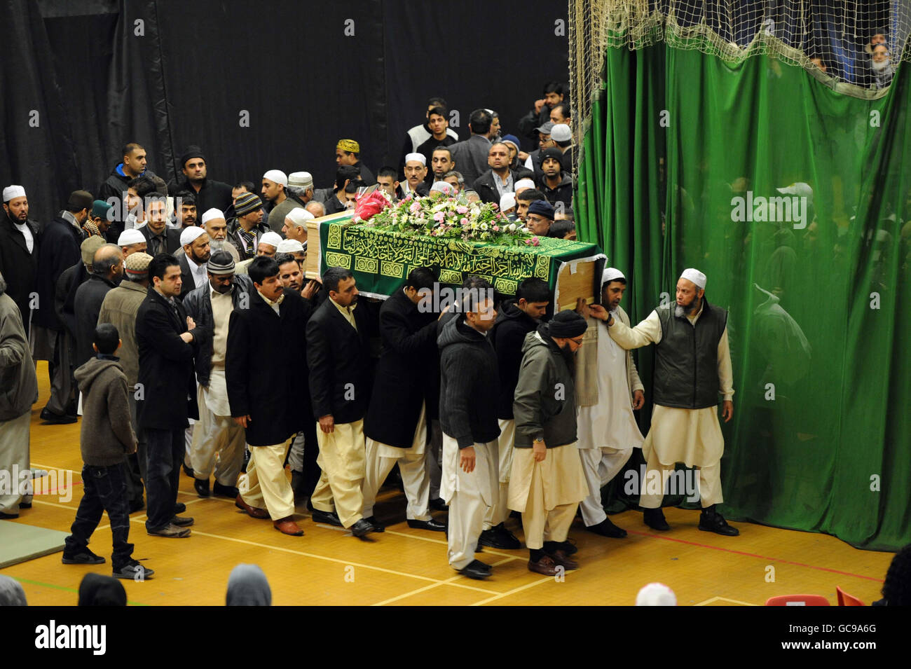 Male mourners carry the coffin past female mourners at the funeral of A ...