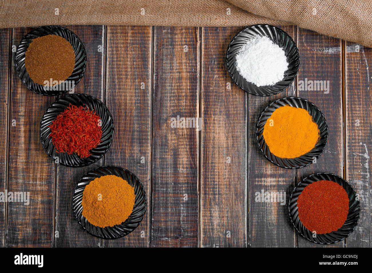 Spices in black ceramic plates on wooden background. Various spices ...