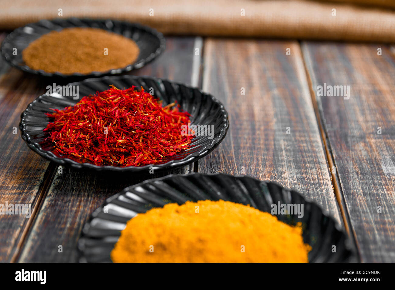 Spices in black ceramic plates on wooden background. Various spices ...