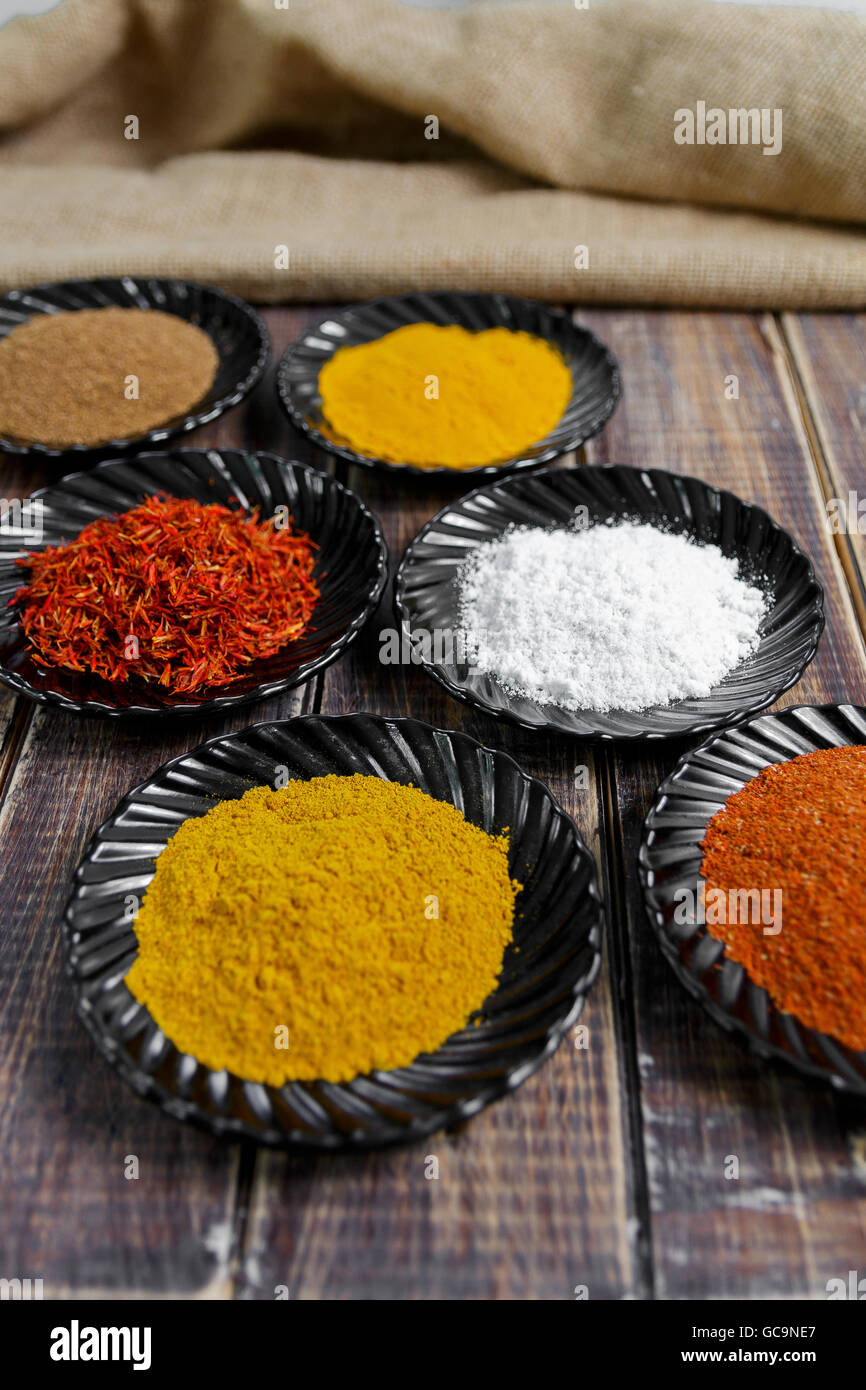 Spices in black ceramic plates on wooden background. Various spices ...
