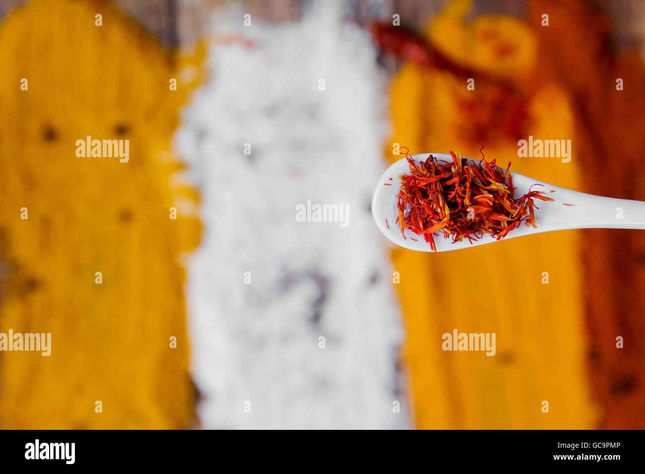 White spoon with saffron on different colorful spices background ...