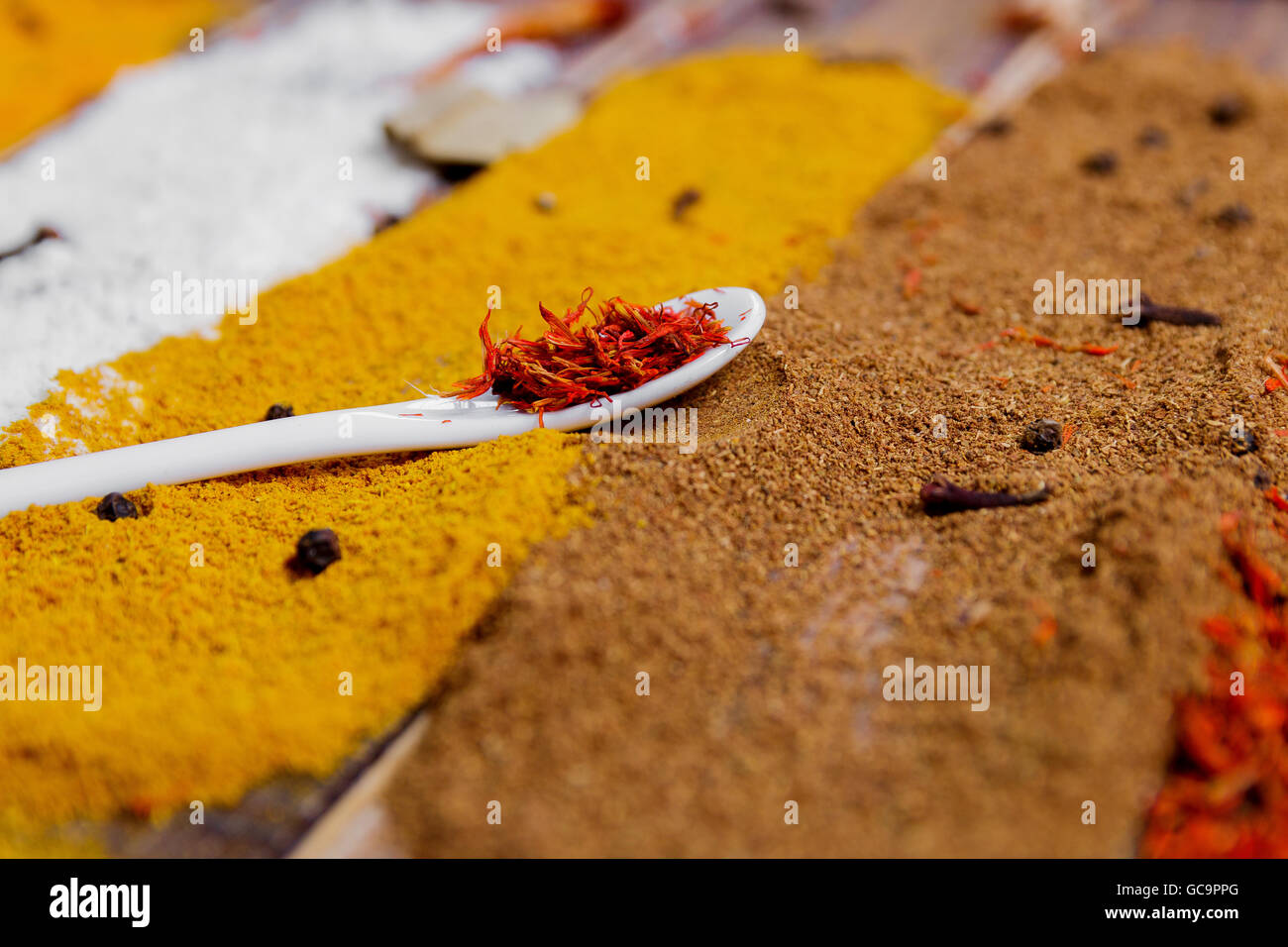 White spoon with shafran on different colorful spices background ...