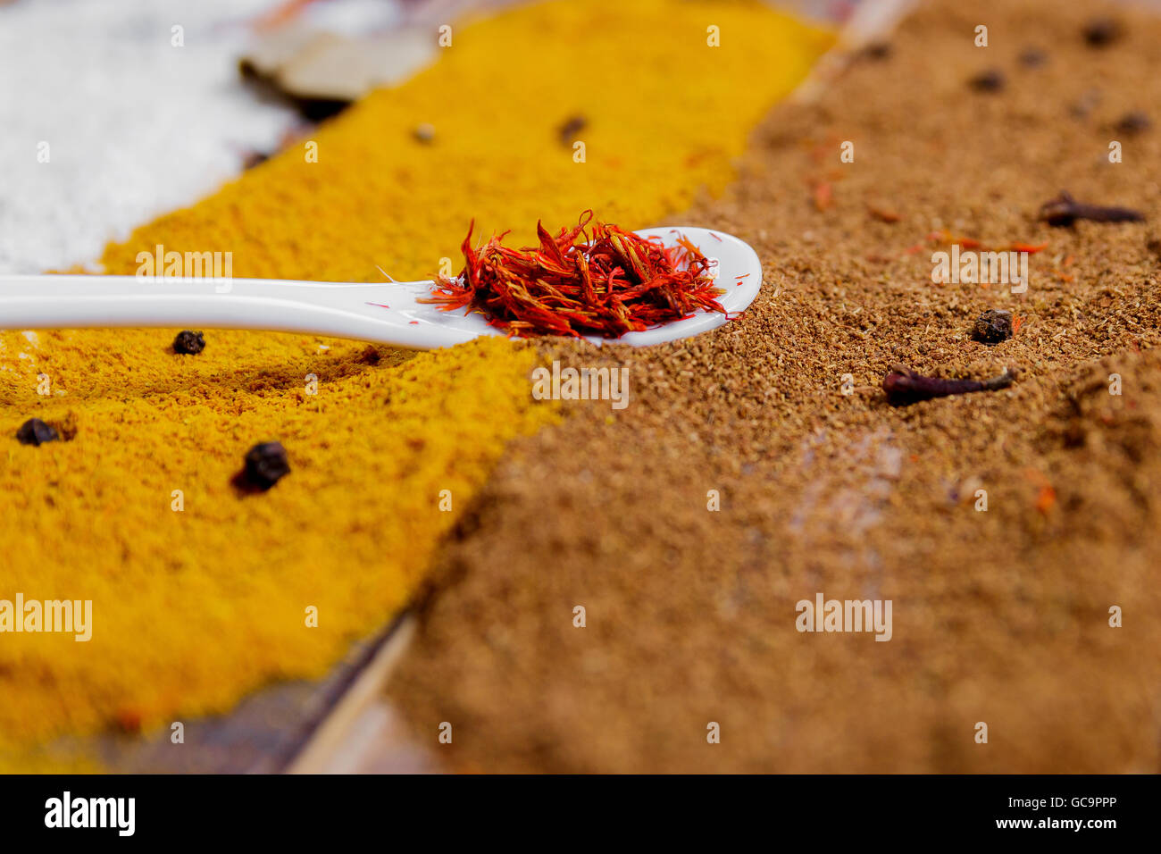 White spoon with shafran on different colorful spices background ...