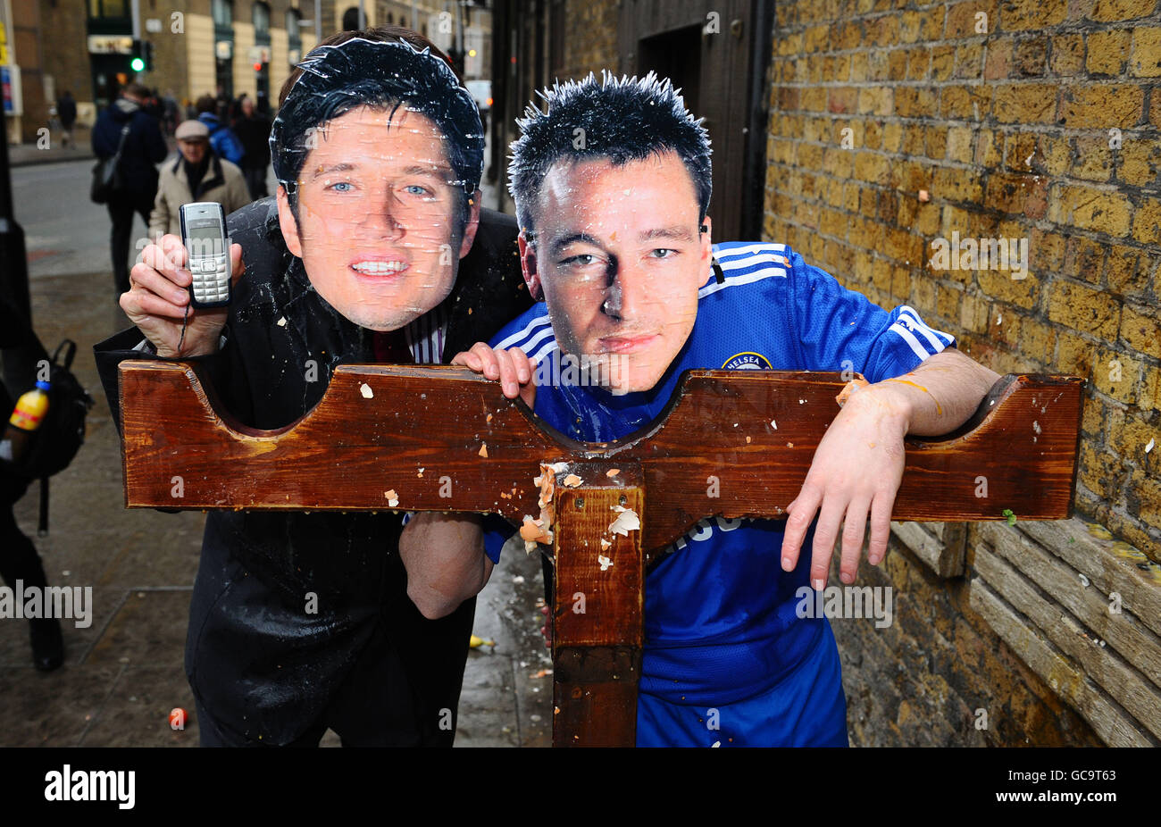 Two men in Vernon Kay and John Terry masks are put in the stocks and ...