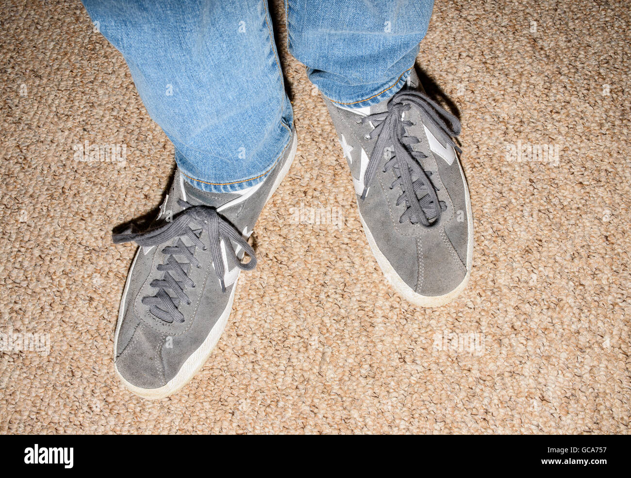 Close up of lower legs and feet of person wearing blue denim jeans and ...