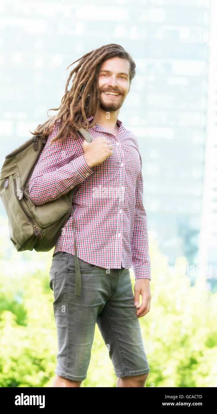 Handsome young man walking in city with backpack on one shoulder Stock ...