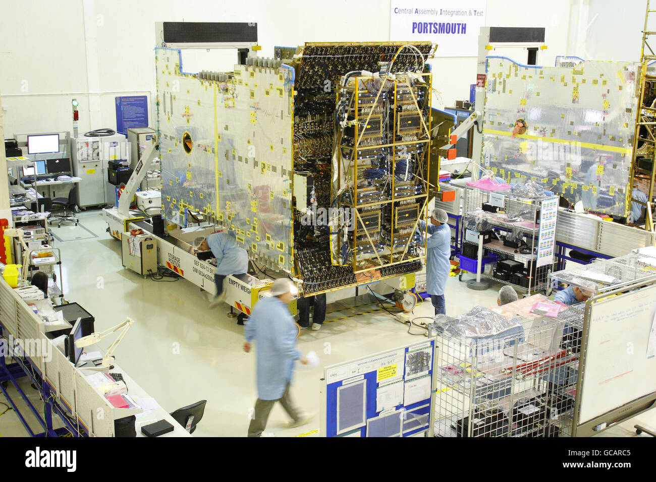 Engineers work on a KA band satellite in the Neptune clean room at ...