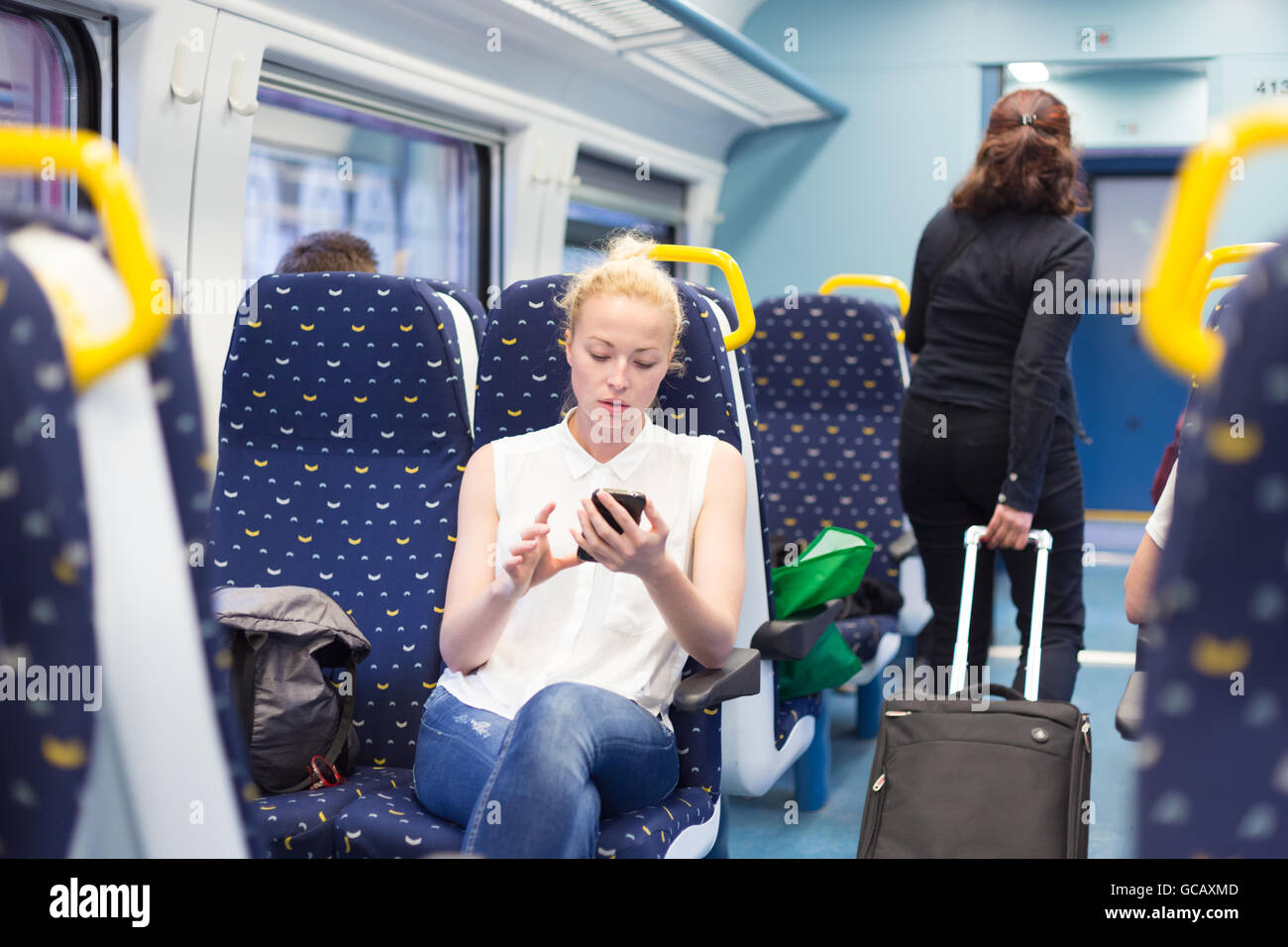Woman using mobile phone while travelling by train Stock Photo - Alamy