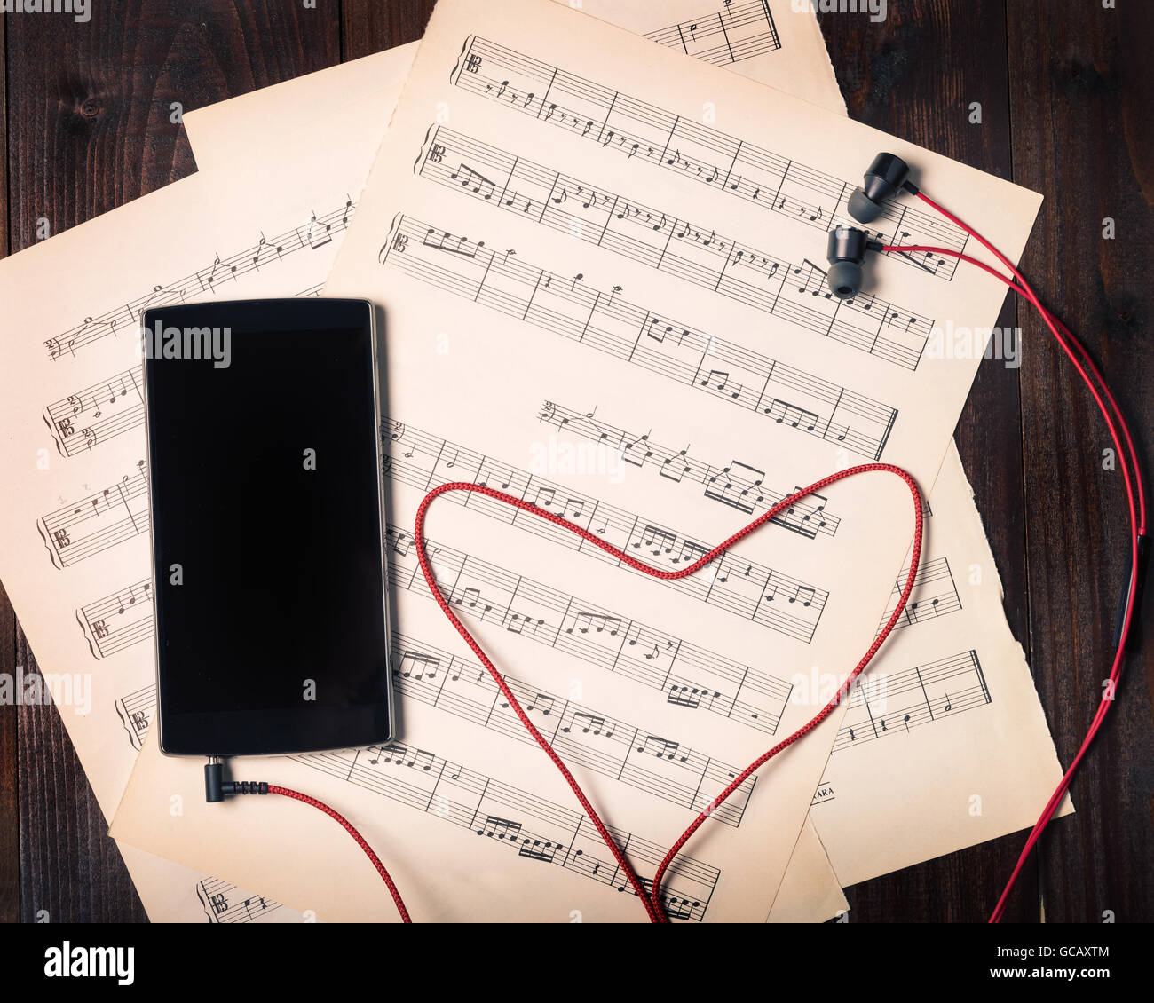 pictured black phone with headphones placed over sheets music ...