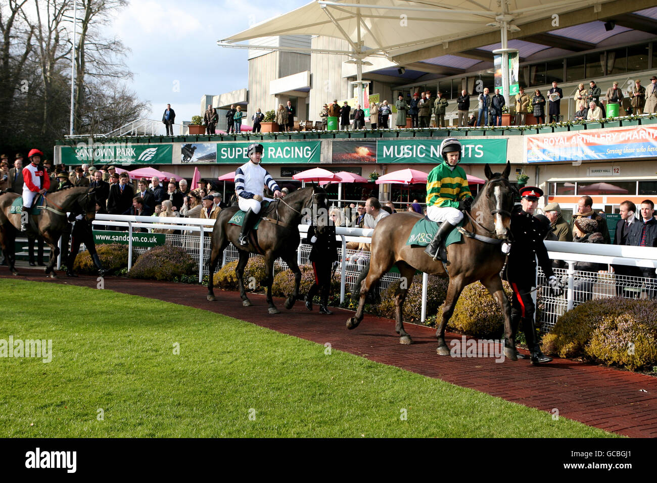 Horses and jockeys are led around the parade ring hi-res stock ...