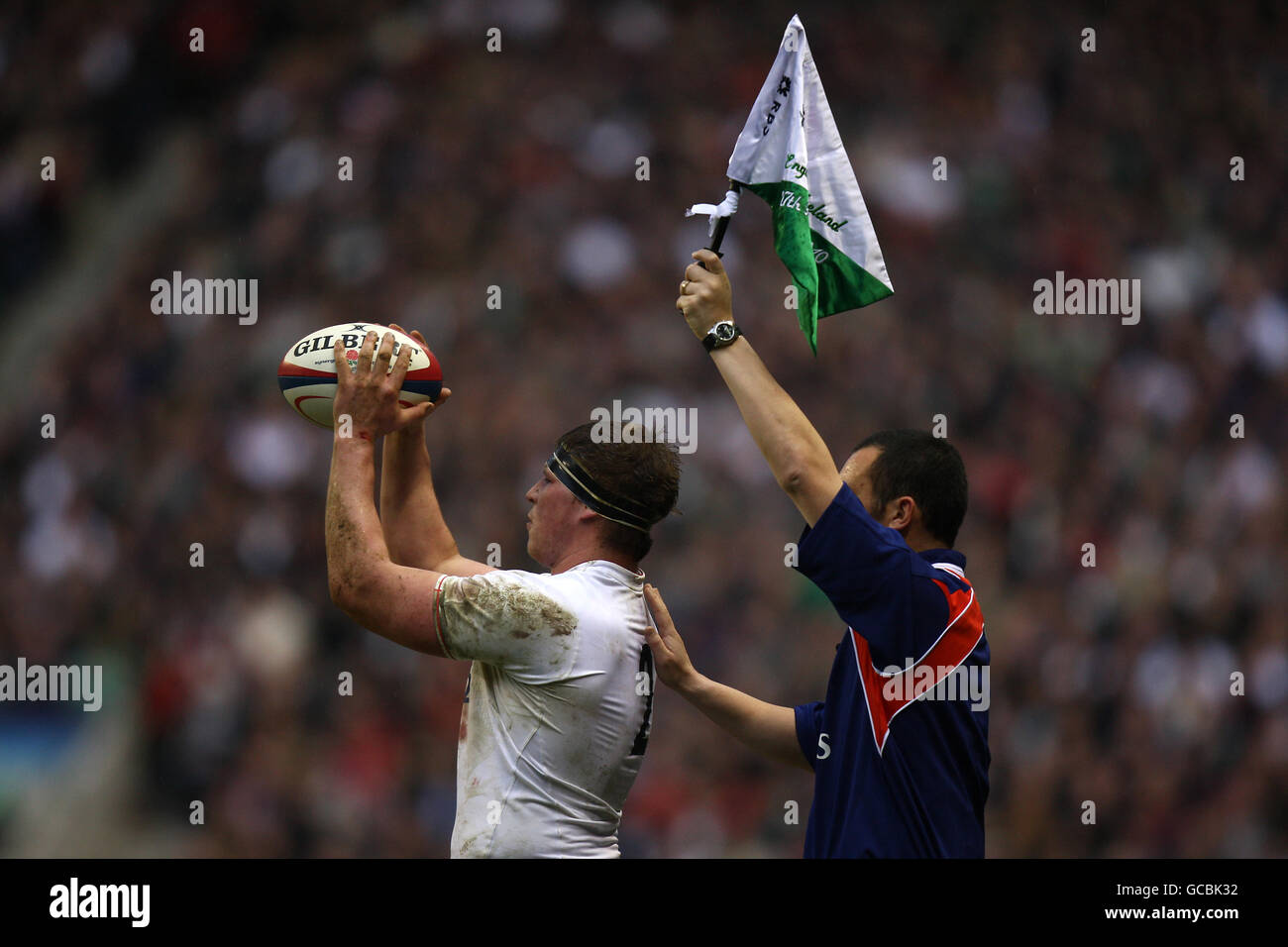 The touch judge with a raised flag places a hand on the back of England ...