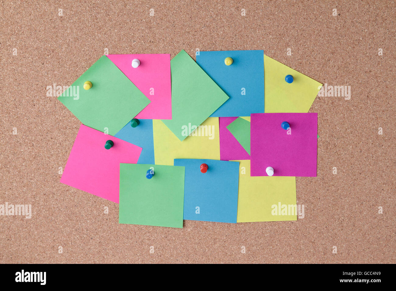 background of colored notes with colored push pins on a cork board ...