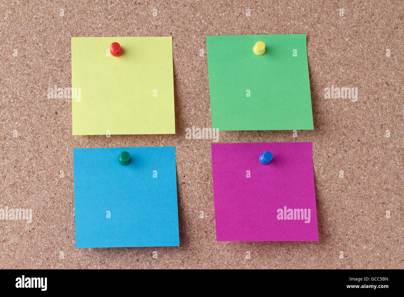 four colored notes with colored push pins on a cork board Stock Photo ...
