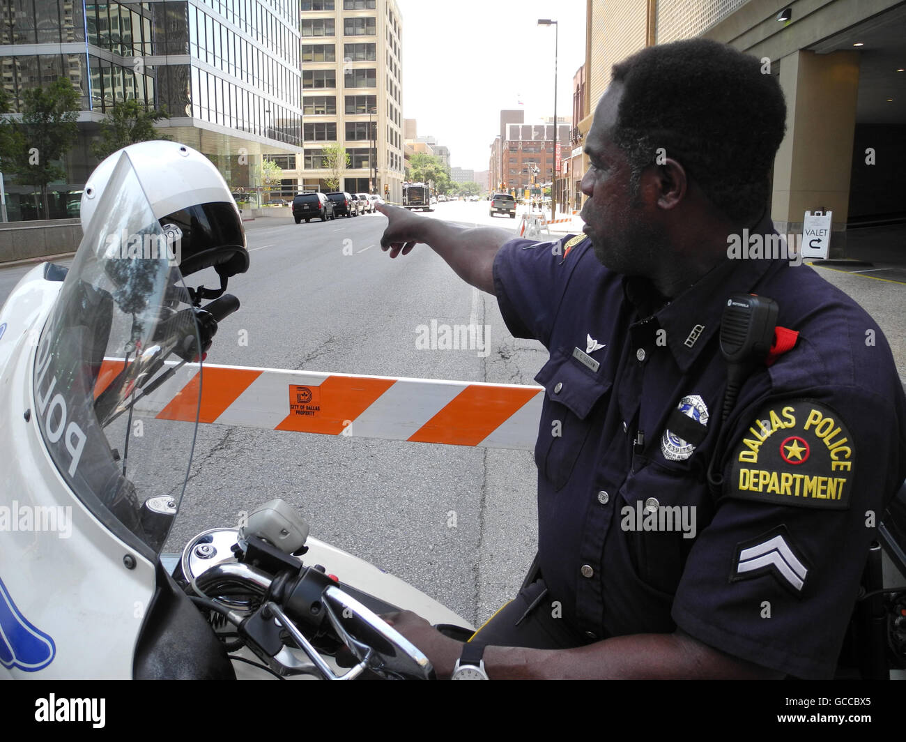 Dallas, US. 8th July, 2016. A police officer on a motorcycle points to ...