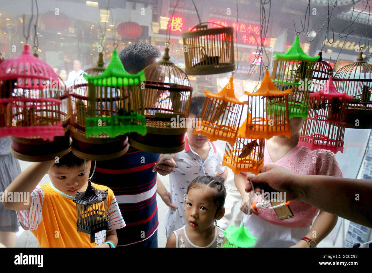 Shanghai. 9th July, 2016. Children get attracted by crickets in tiny ...