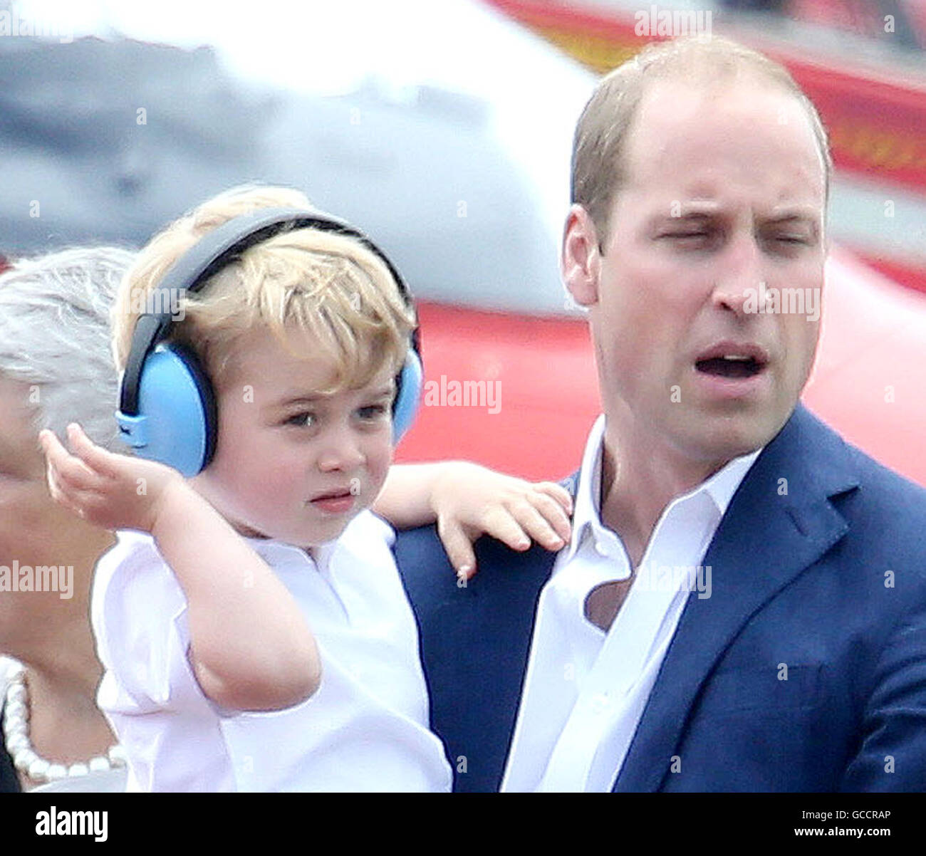 Prince George wears a set of ear defenders as he is carried by his ...