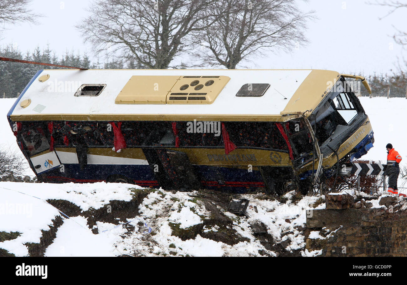 A recovery worker stands besides the crashed school bus after it was ...