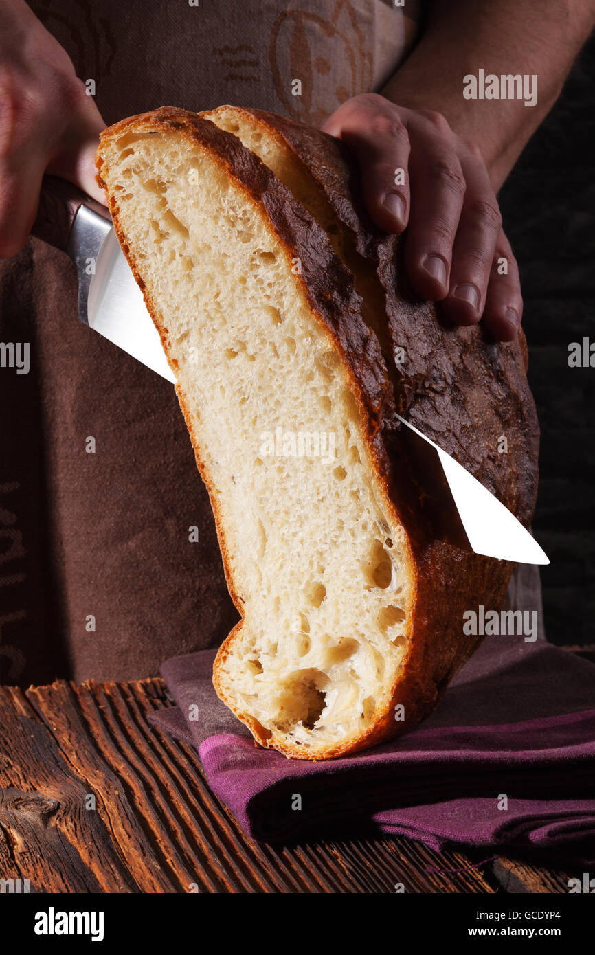 Baker cutting and holding fresh made bread isolated on white background ...