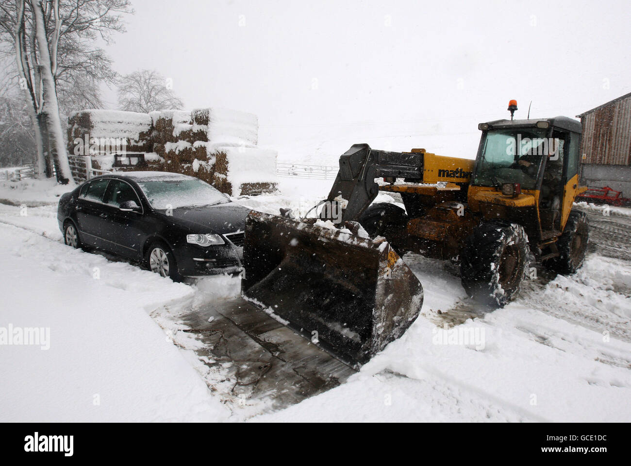 A farmer clears snow from the main street in Carronbridge, central ...