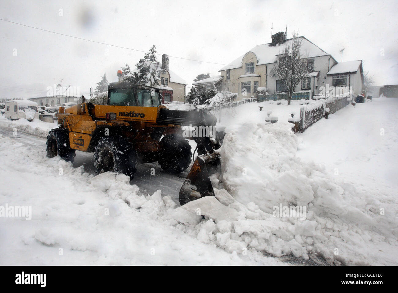 A farmer clears snow from the main street in Carronbridge, central ...